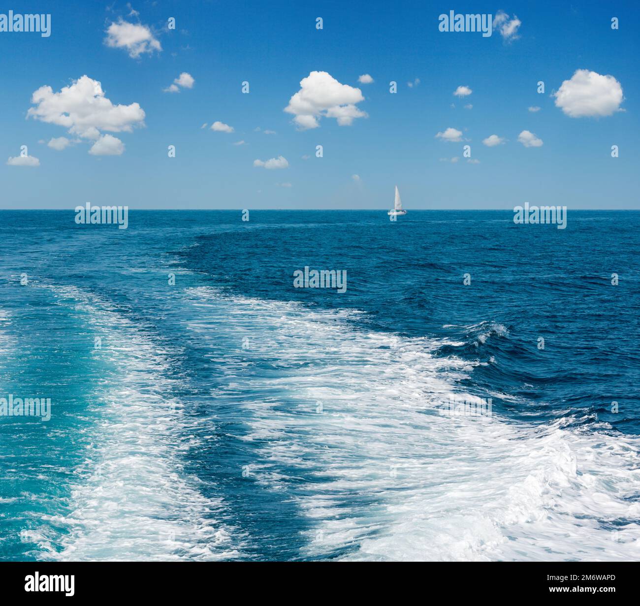 Trace on water surface in the sea and sailing vessel in far Stock Photo ...