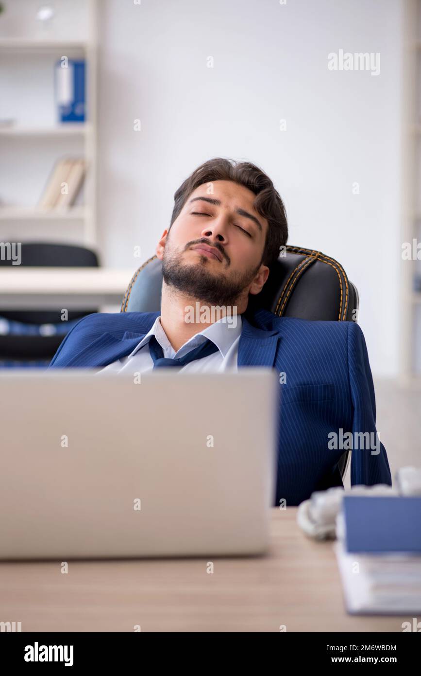 Young male employee extremely tired in the office Stock Photo - Alamy