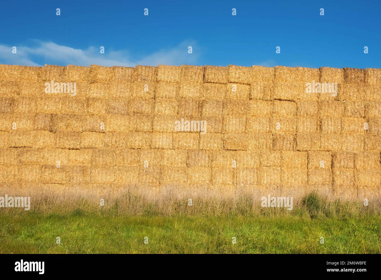 A tall stack of hay bales and blue sky Stock Photo - Alamy