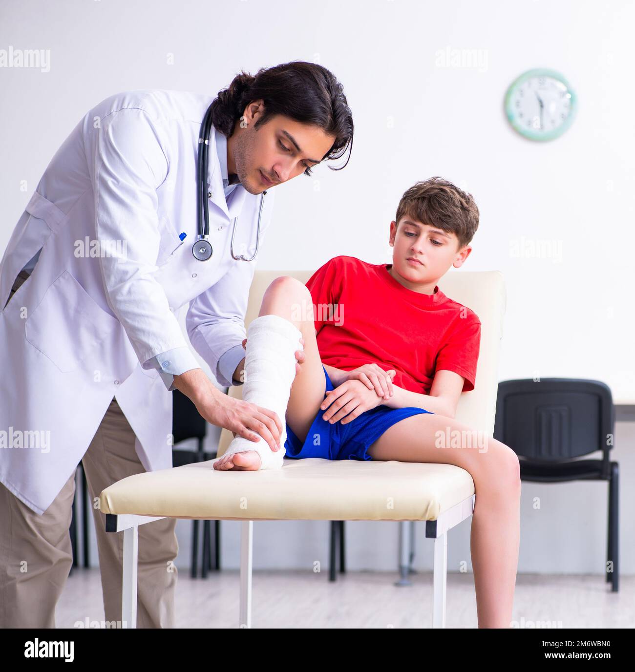 Leg injured boy visiting young doctor traumatologist Stock Photo - Alamy