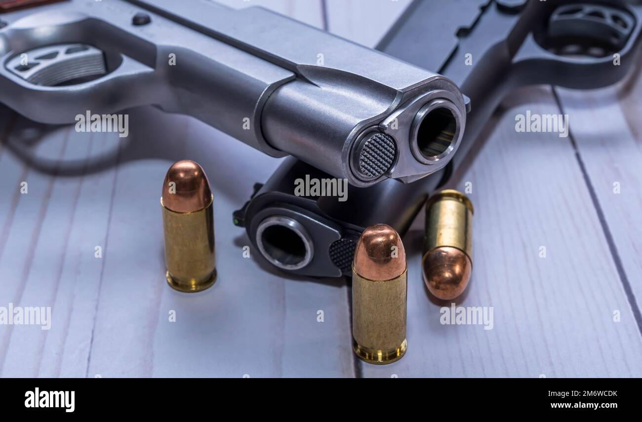 The muzzles of two different 1911 pistols chambered in 45acp, one black and the other stainless ...
