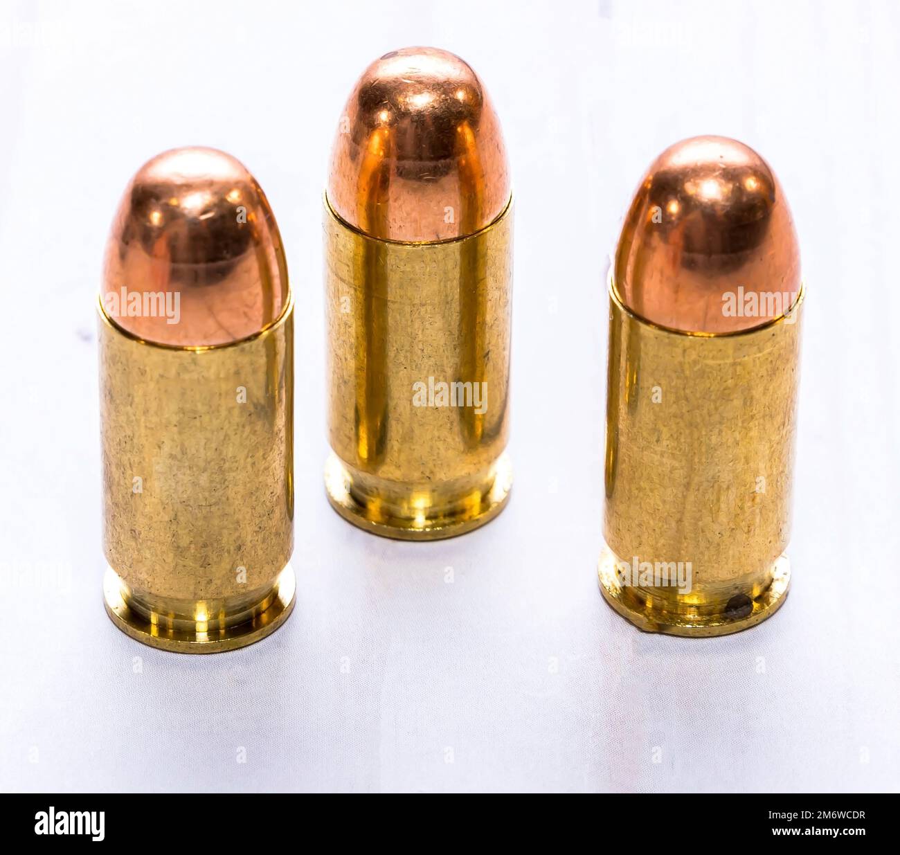Three 45acp full metal jacket handgun bullets together on a white ...