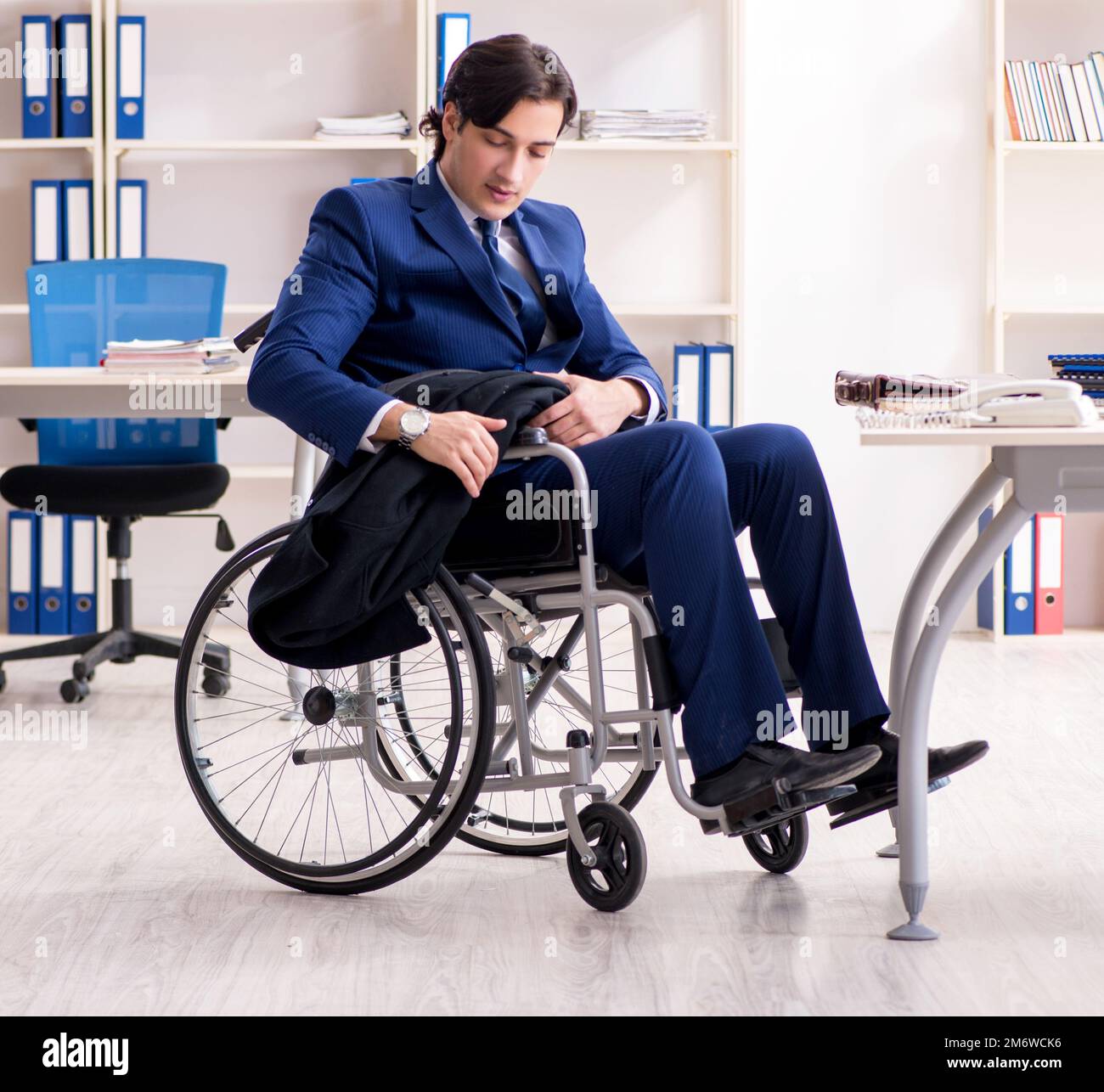 Young male employee in wheelchair working in the office Stock Photo - Alamy