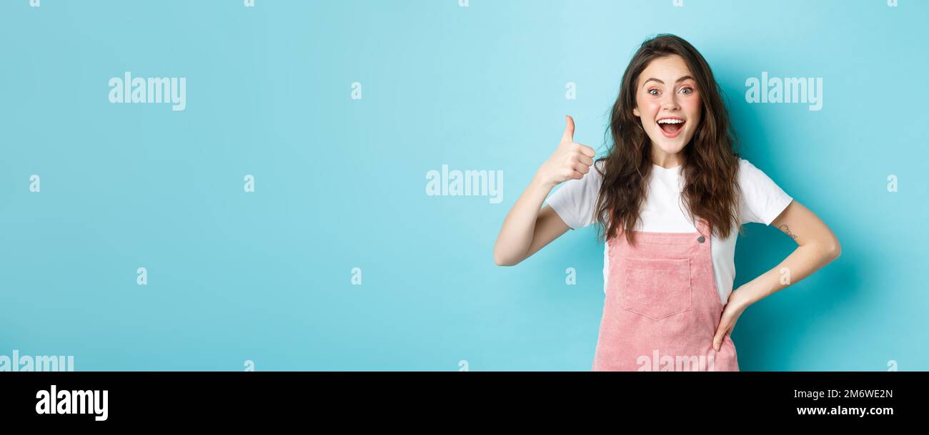 Portrait of surprised and excited brunette girl showing thumb up and ...