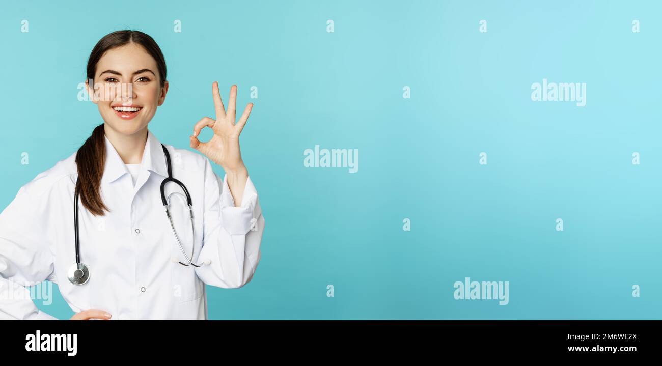 Portrait of satisfied, smiling medical worker, woman doctor showing ...