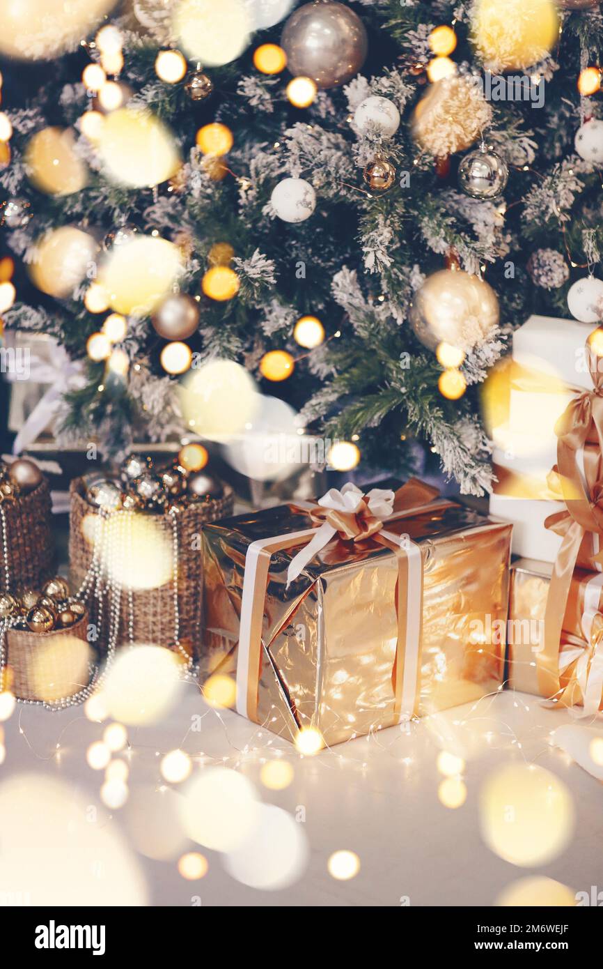 Close up of wrapped golden gift box with bow on floor under Christmas ...