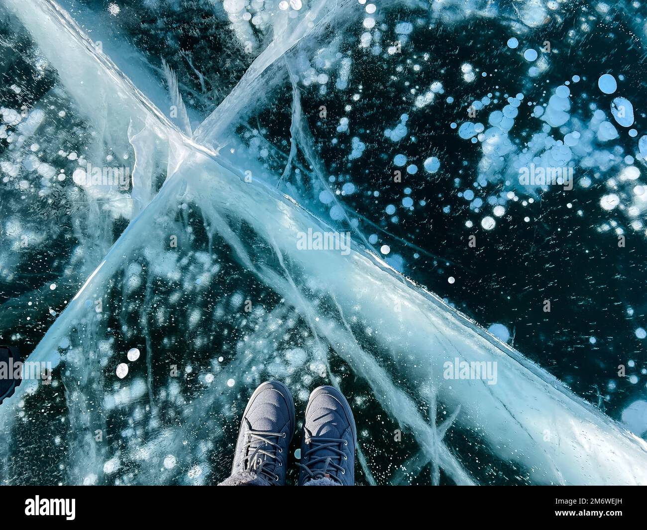 Fragile thin brittle ice underfoot. Female feet on ice. Woman wearing ...