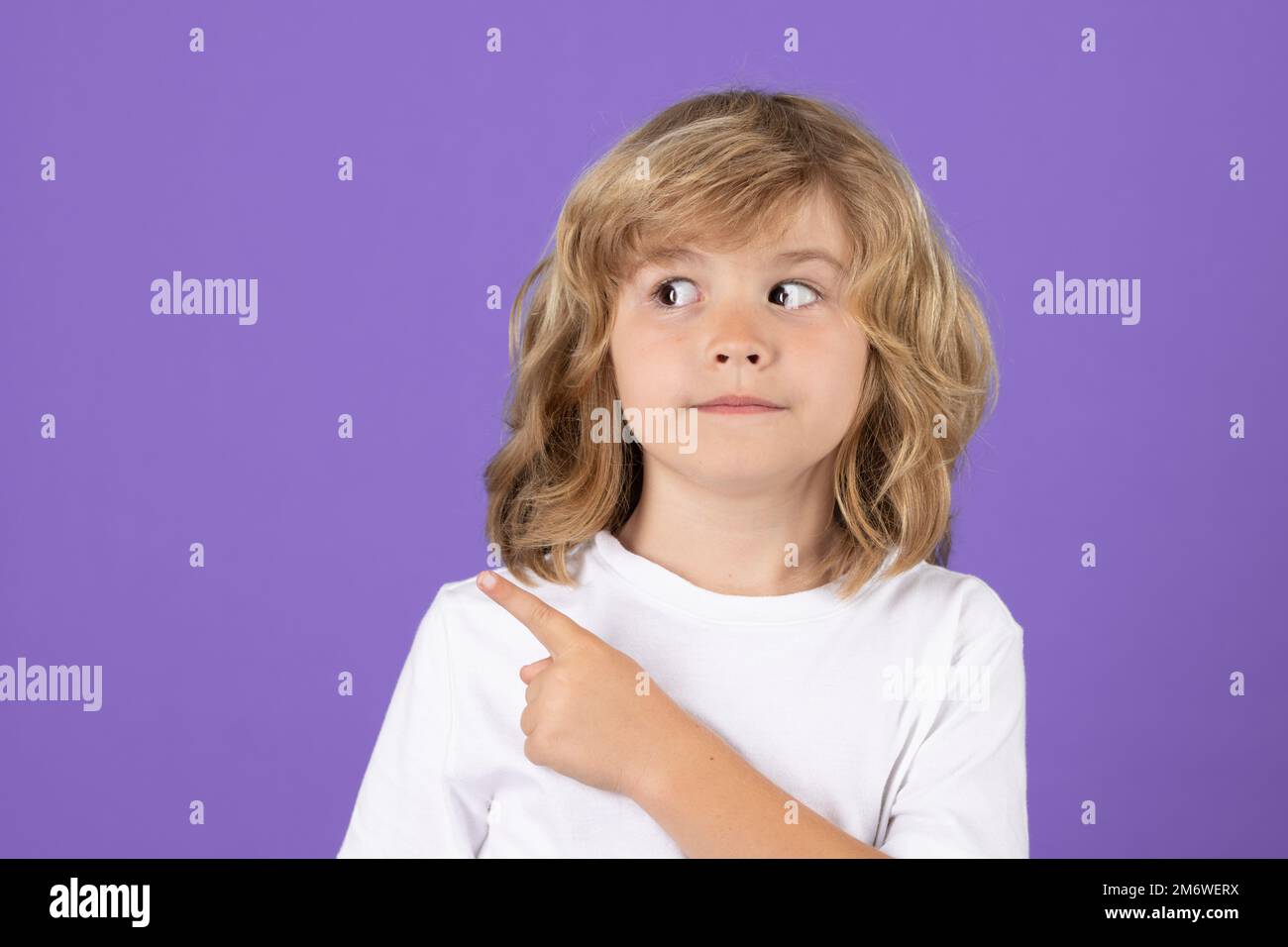 Little child looking away, pointing finger on isolated studio ...
