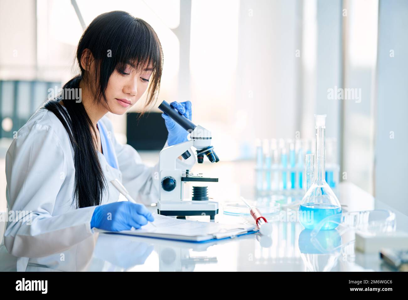 Beautiful female scientist analyzing microscope slides working in ...