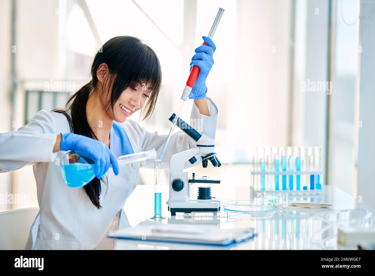 Happy smiling science student making research pouring reagent into test ...