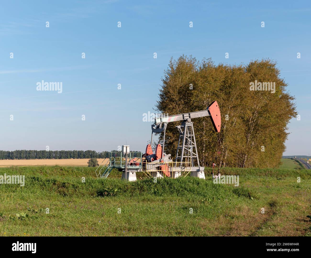 Operating oil and gas well in oil field, profiled against the blue sky ...