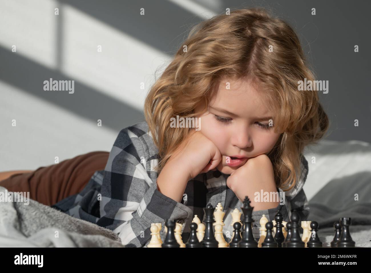 Clever child thinking about chess. Portrait of clever kid with ...