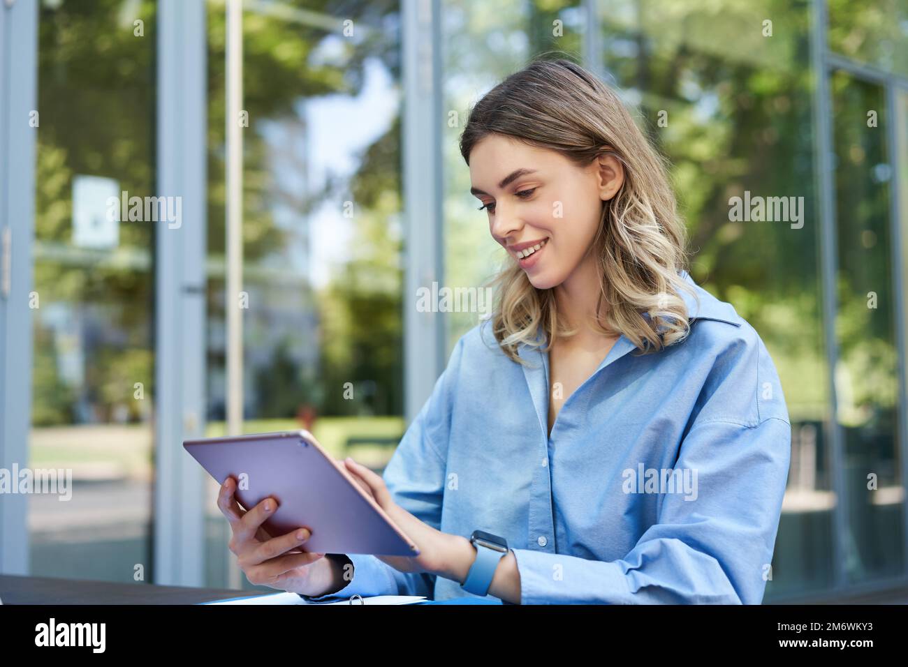 Young digital nomad, woman with tablet, working outdoors on fresh air ...