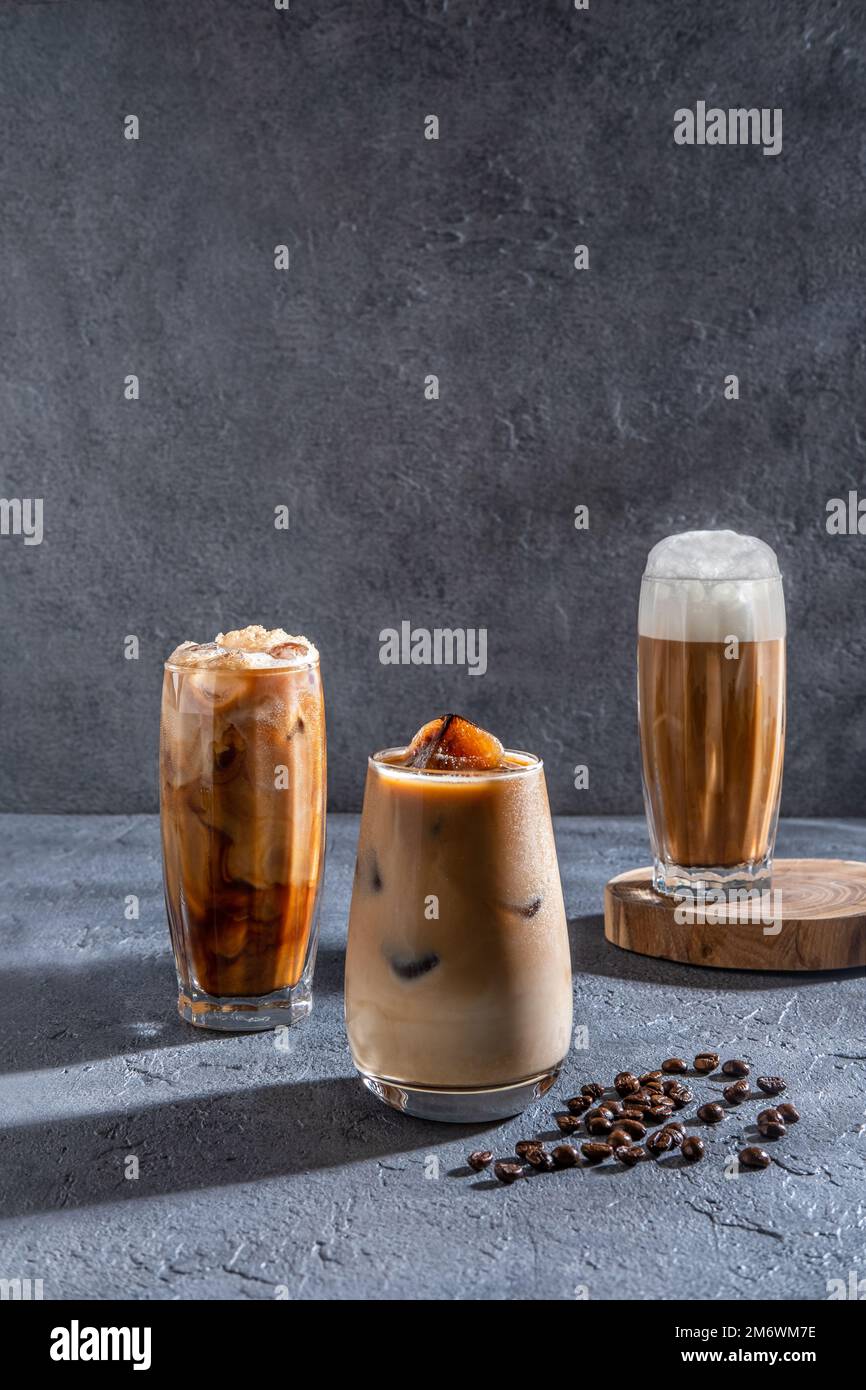 Ice coffee in a tall glass with cream poured over and coffee beans ...