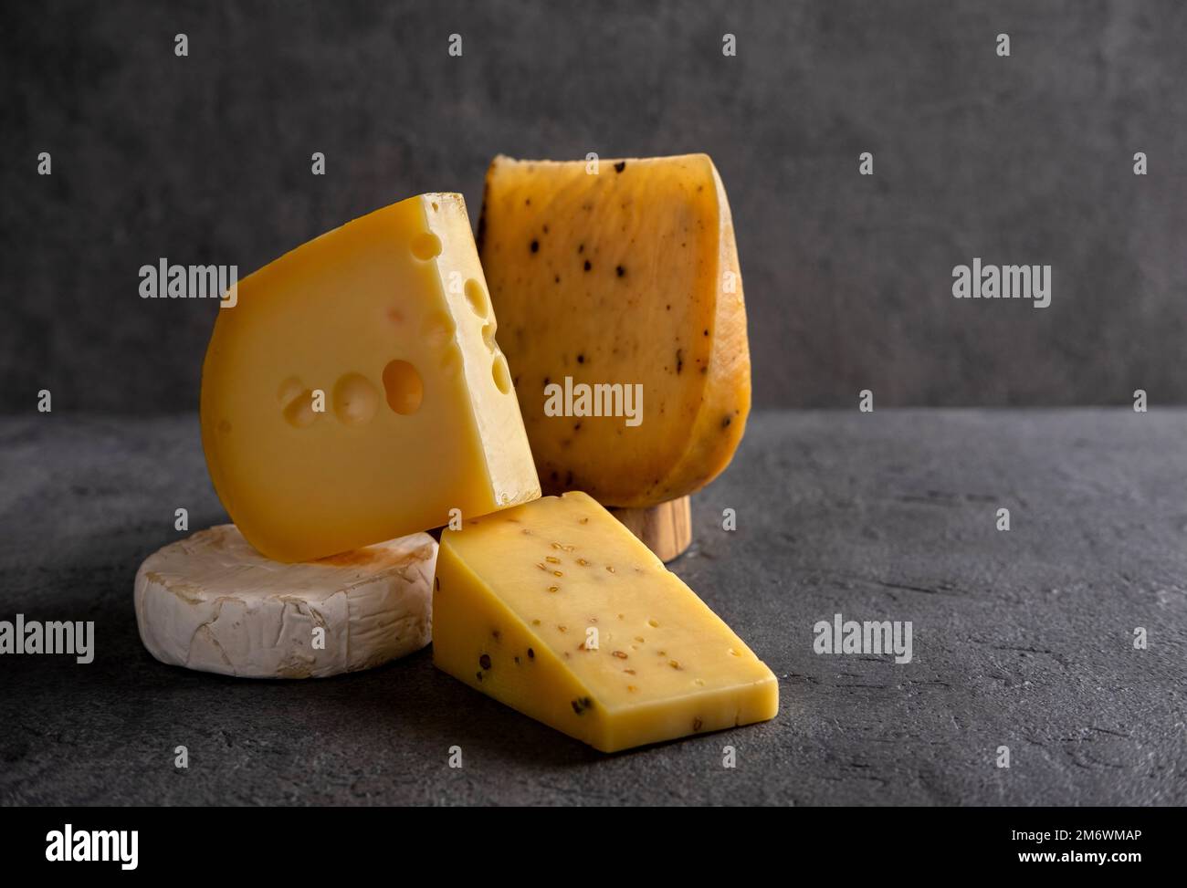 Various types of cheese on grey board. Dark moody. Free space for your ...