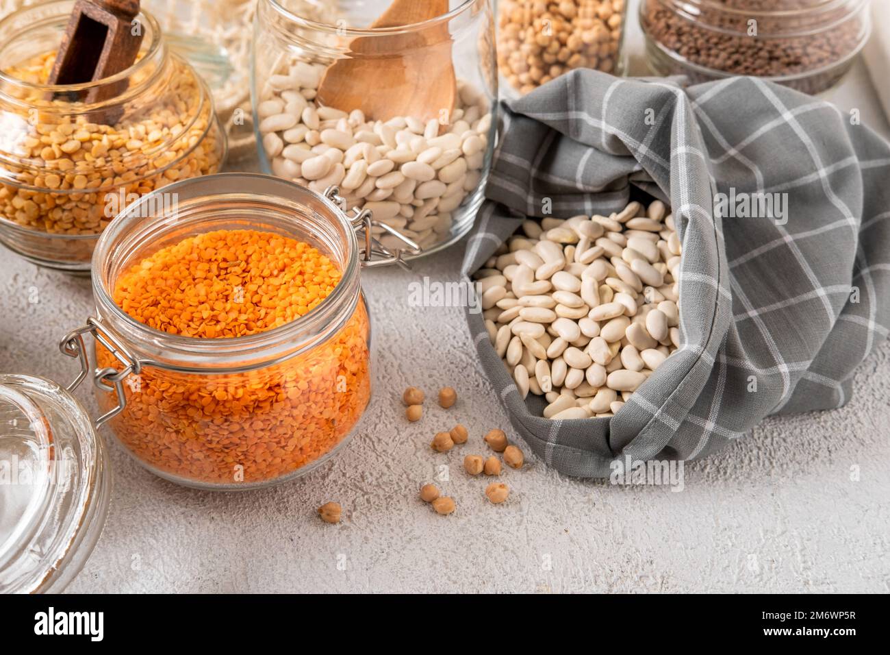 Different legumes in glass jars: chickpeas, pasta, beans, peas, lentils ...
