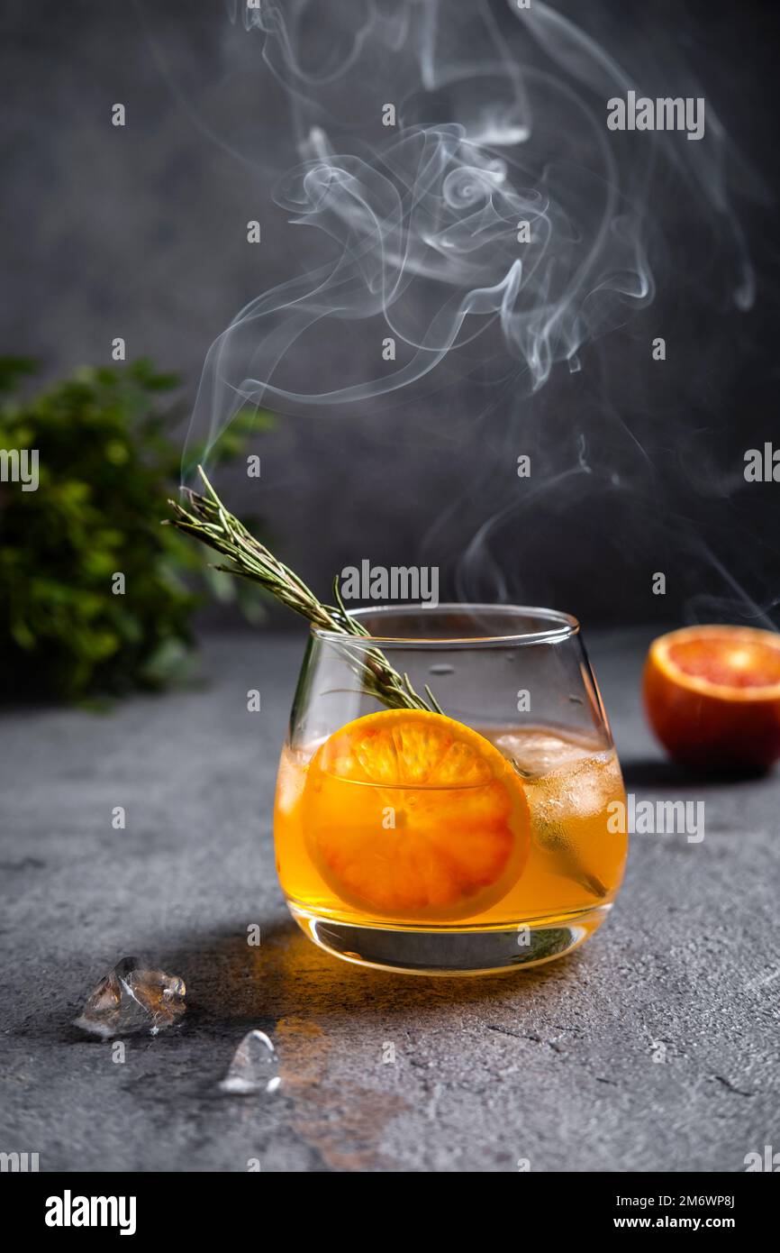 Negroni with smoking rosemary. Negroni with ice and orange on a dark ...