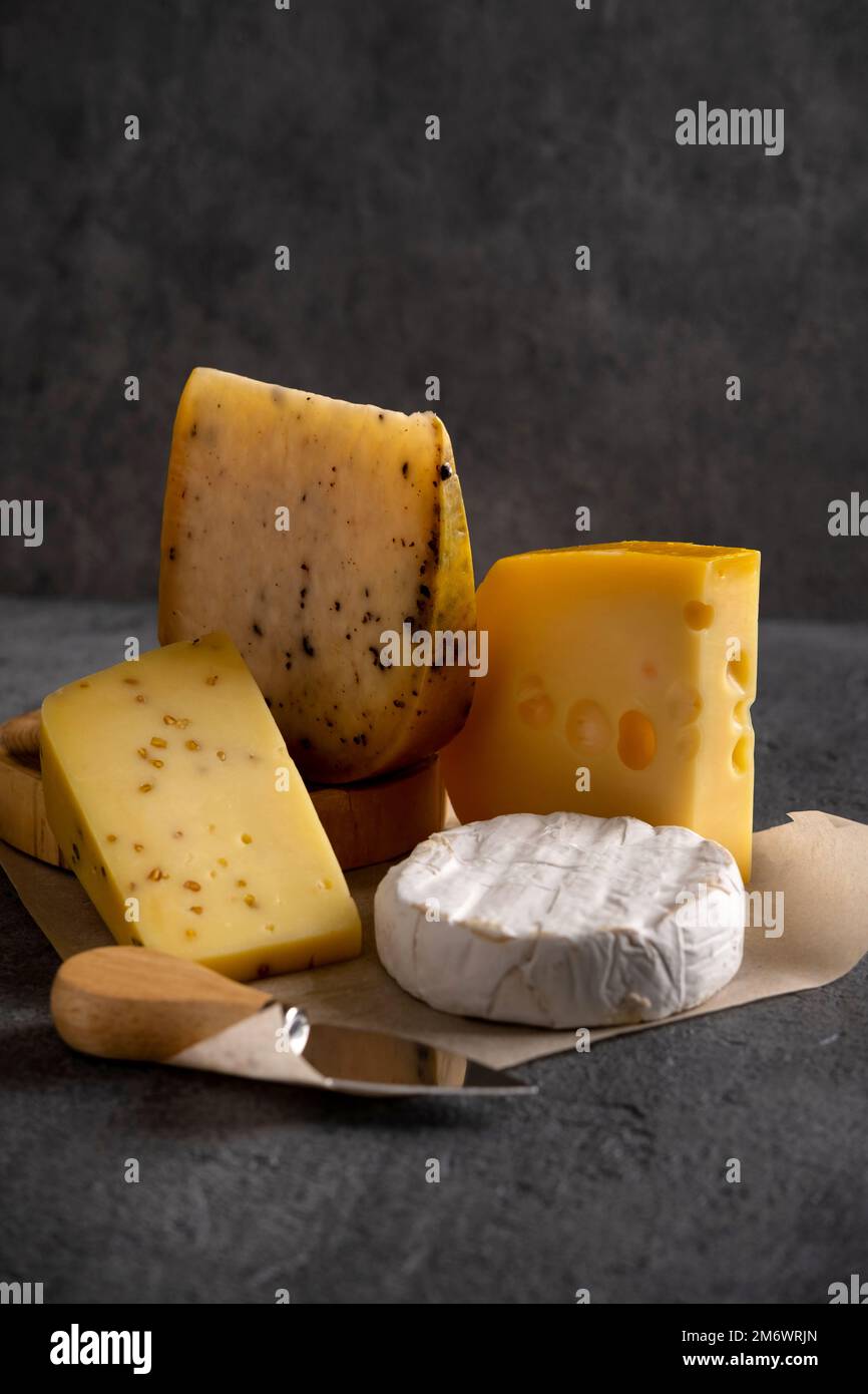 Various types of cheese on grey board. Dark moody. Free space for your ...