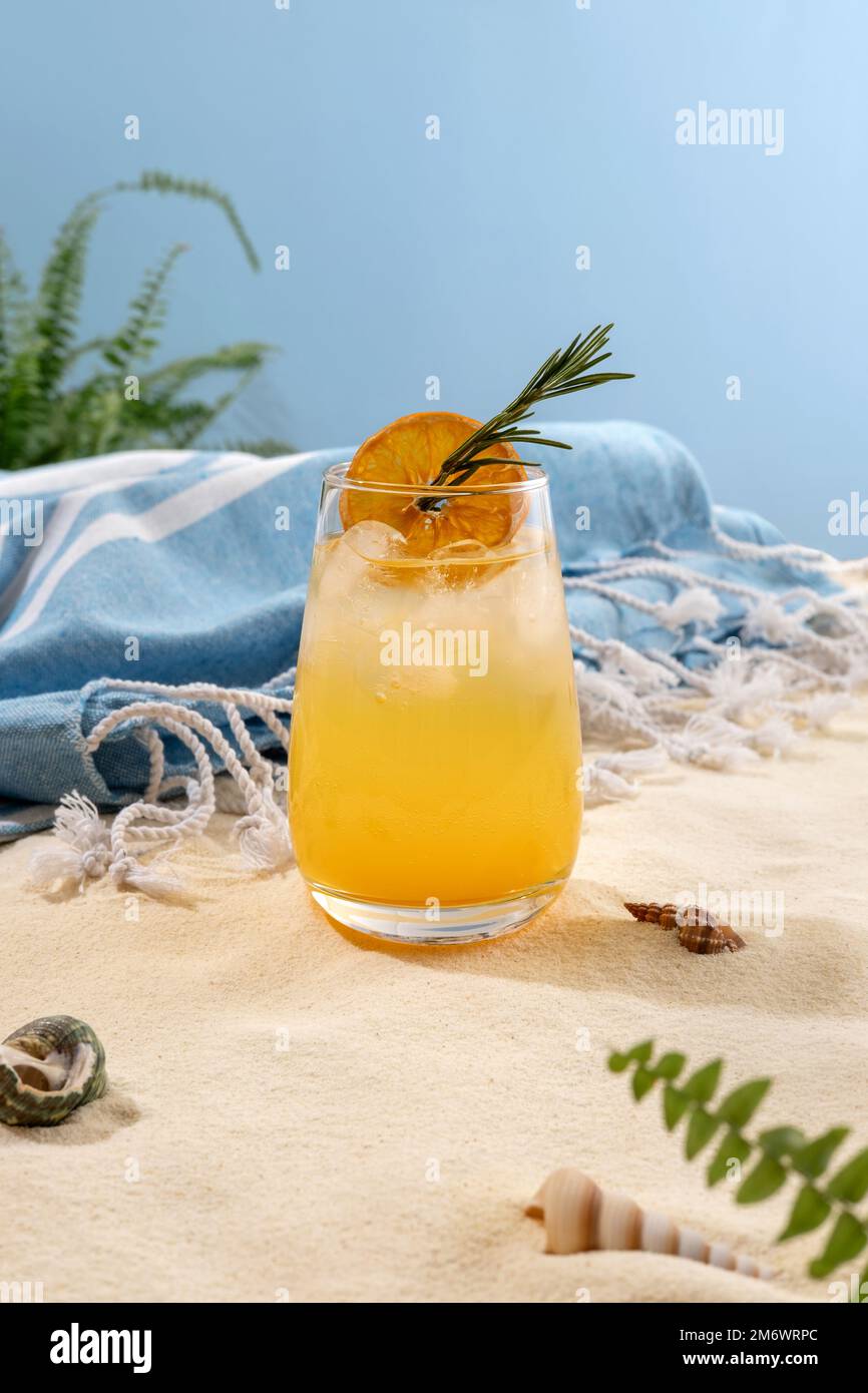 Tequila sunrise cocktail on a wicker tray on beach with white sand ...