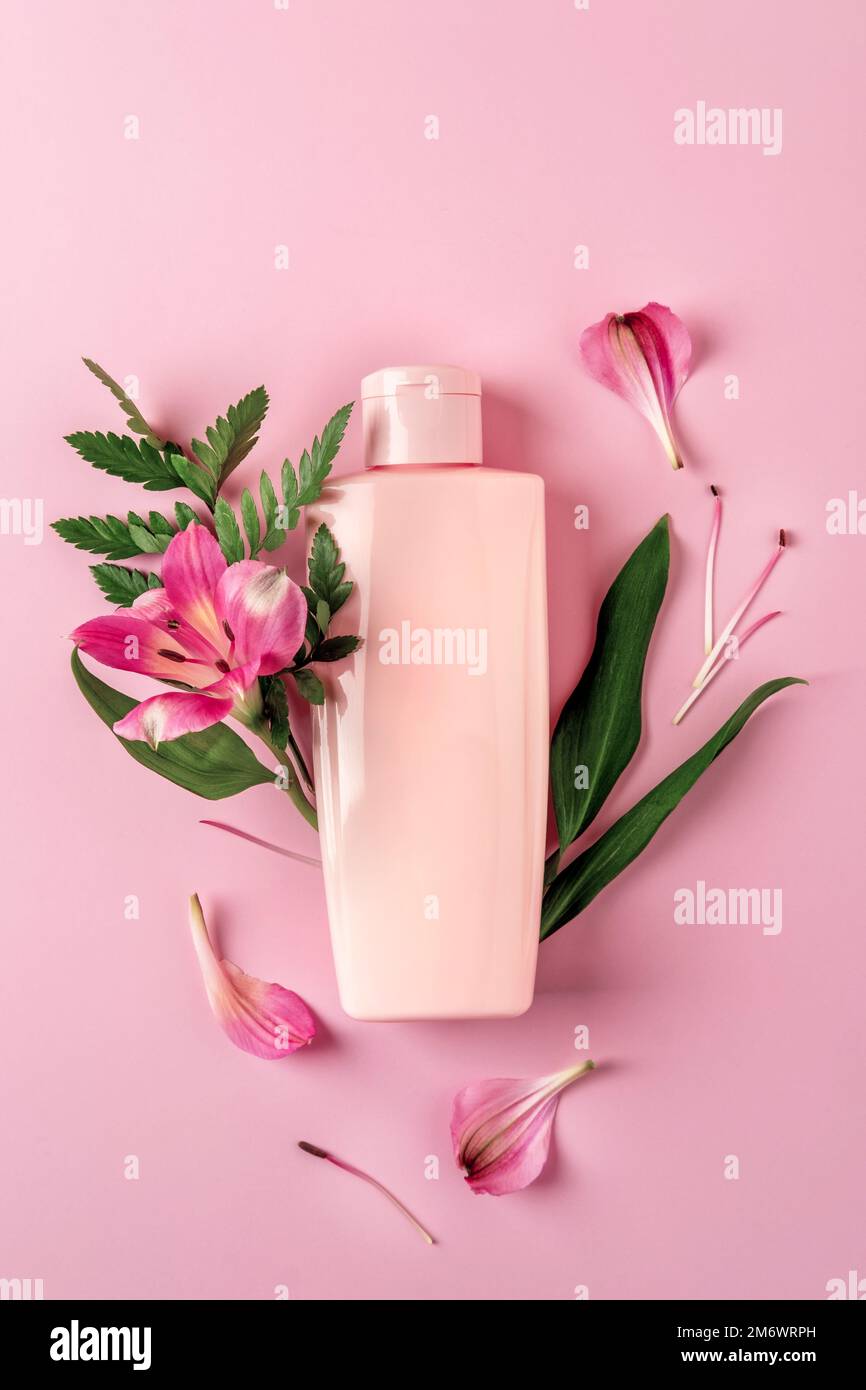 Pink bottle with moisturizer on pink background with flowers ...