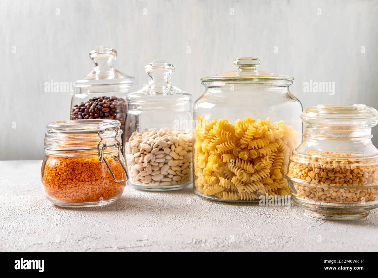 Different legumes in glass jars: chickpeas, pasta, beans, peas, lentils ...