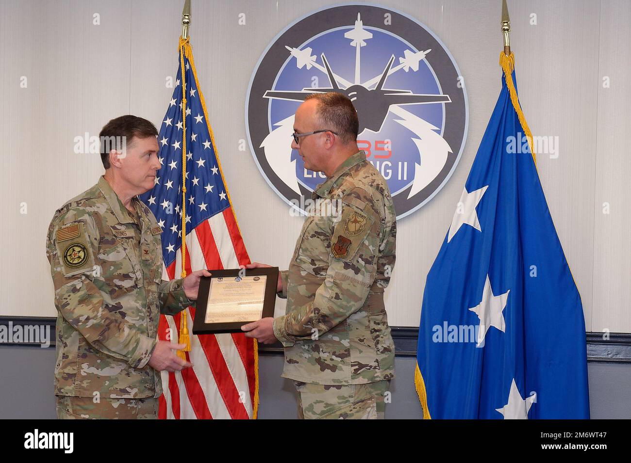 Air Force Col. Robert Lyons (left), receives a framed copy of his ...