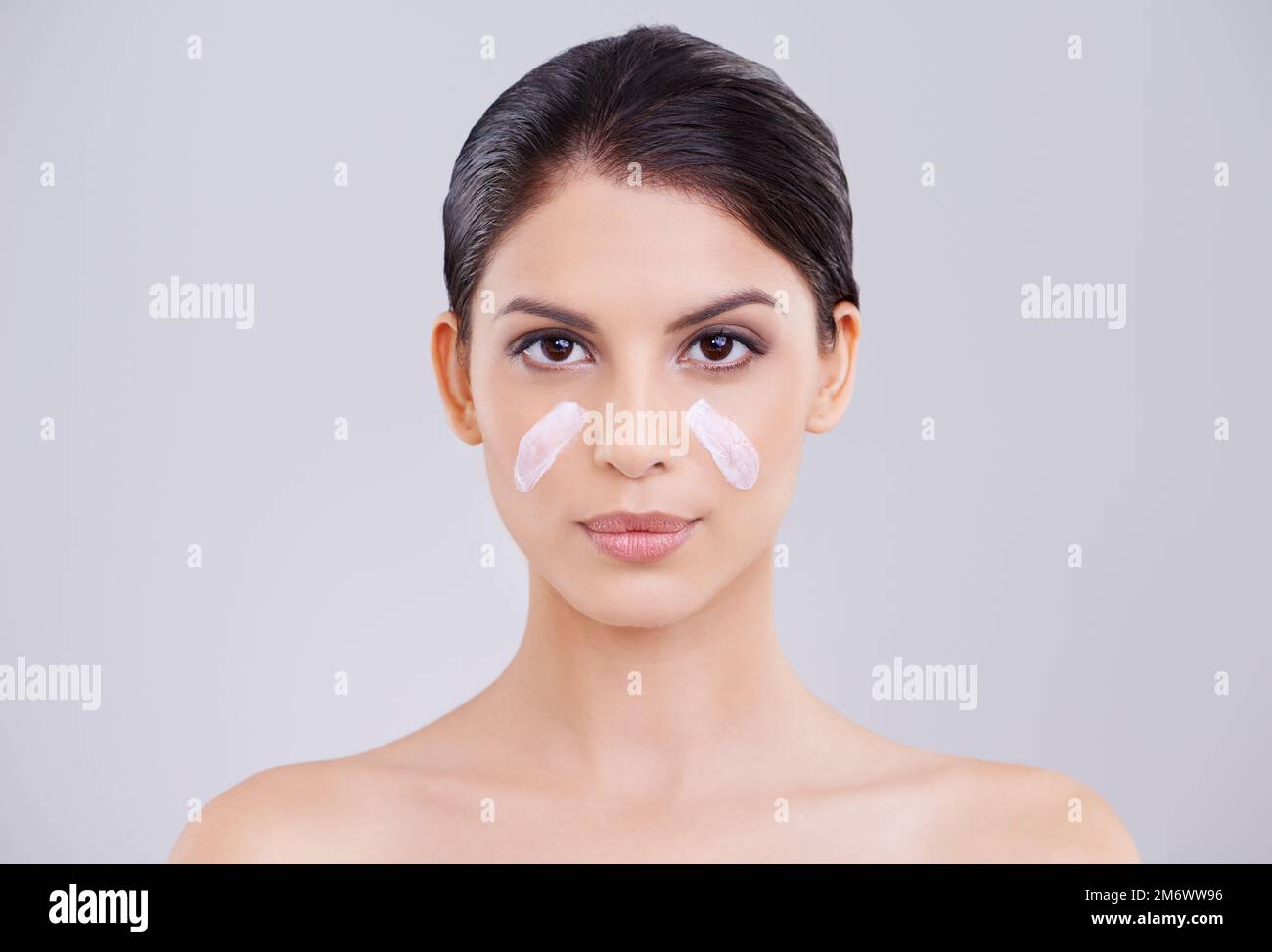 Looking after her skin. a beautiful young woman with moisturizer on her ...