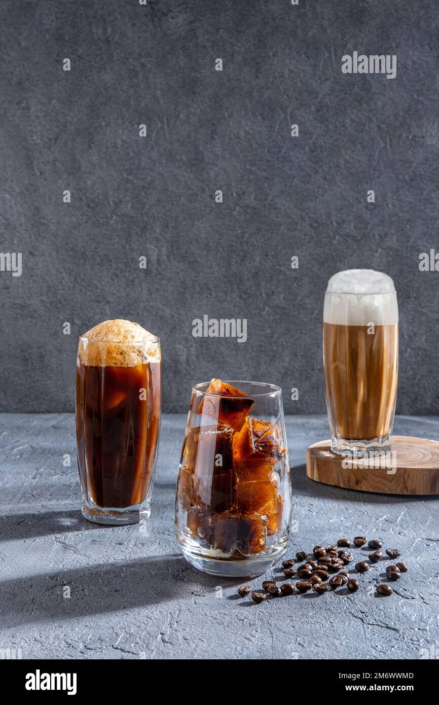 Ice coffee in a tall glass with cream poured over and coffee beans ...