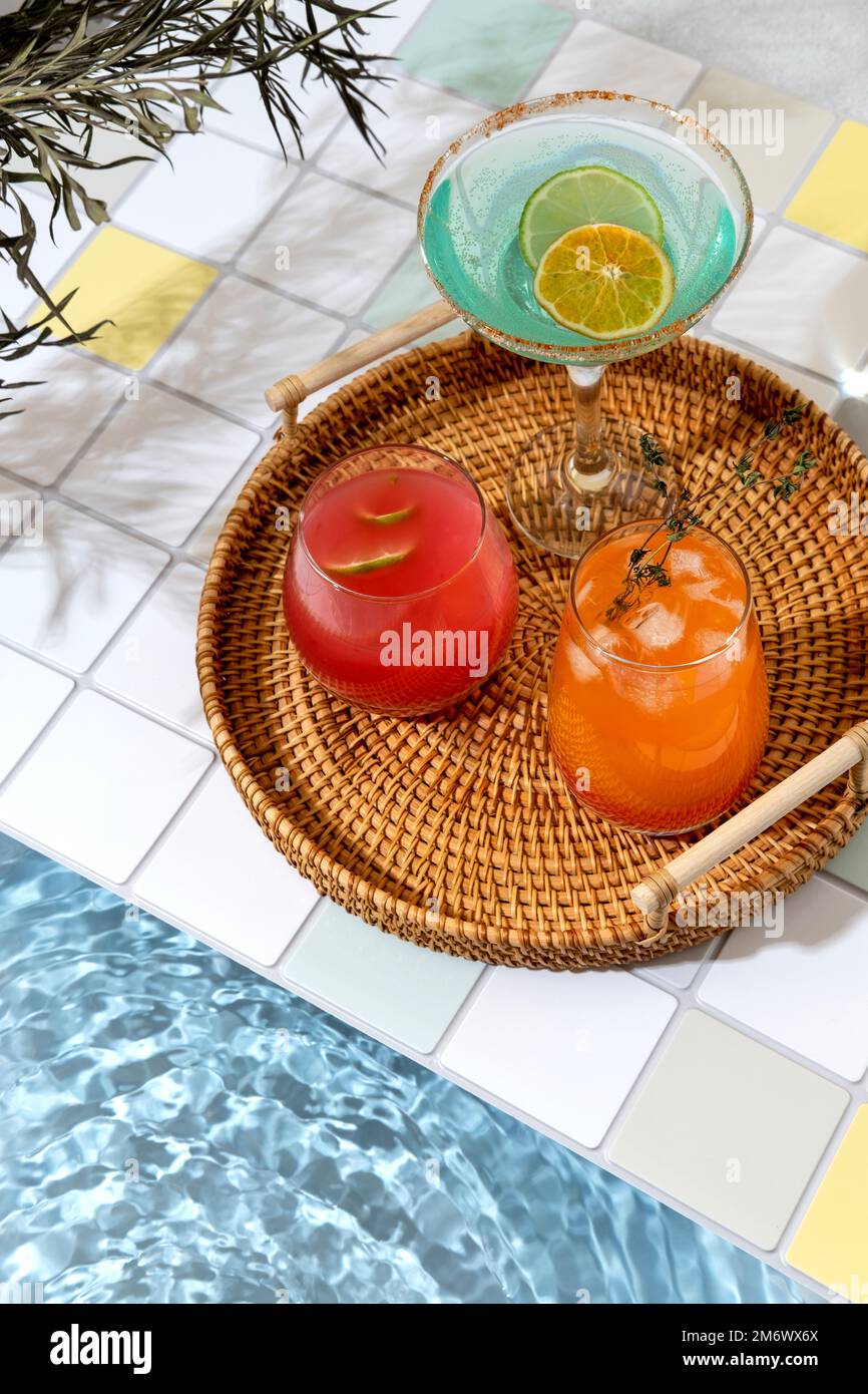 Three Ñ olorful tropical cocktail on edge of swimming pool. Summer ...