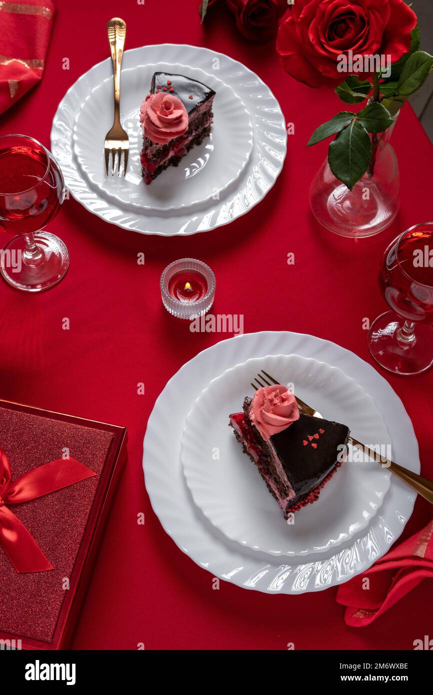 Valentines day dinner with table place setting with red gift, red roses, with chocolate cake ...