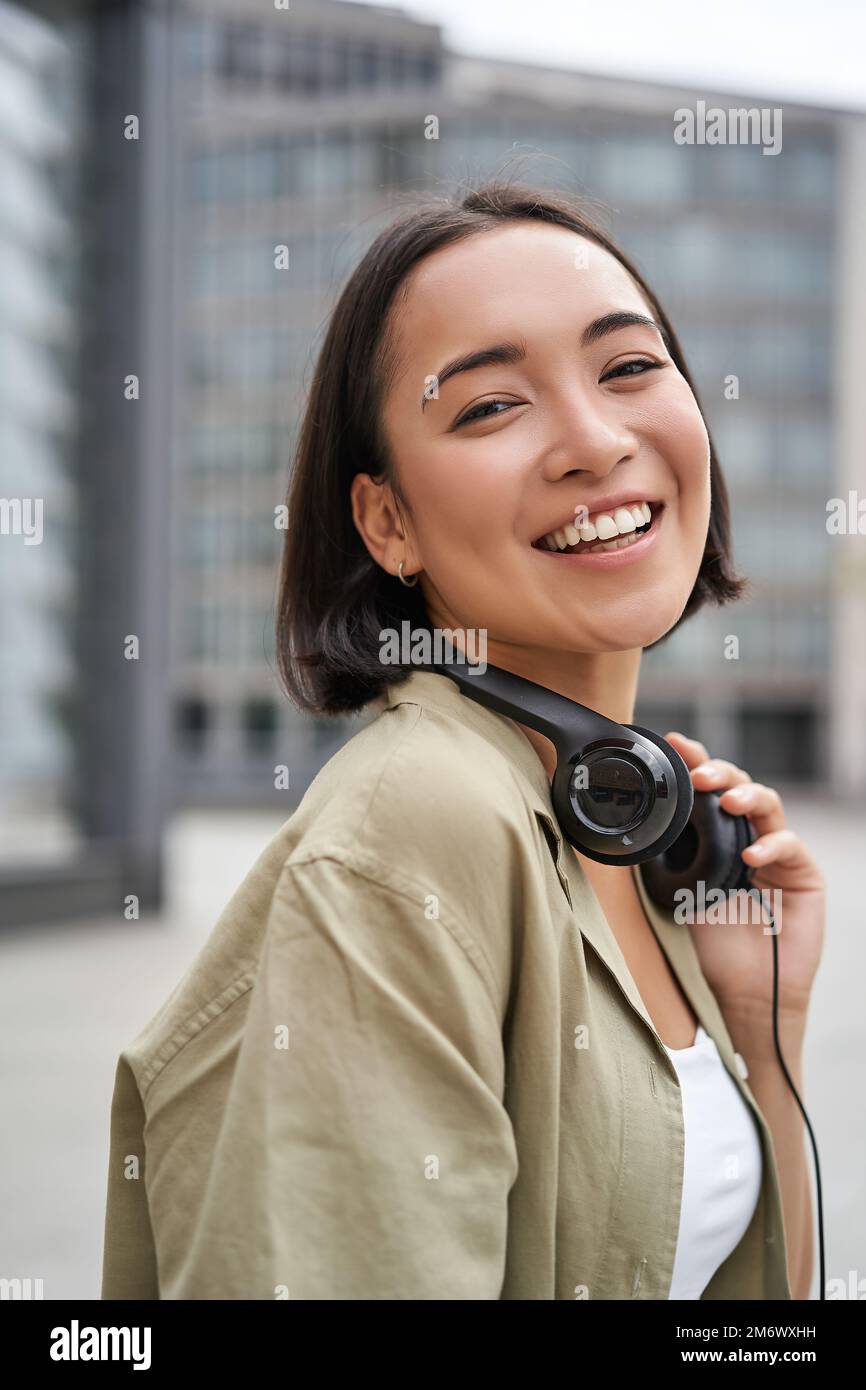 Vertical shot of beautiful asian woman posing with headphones around ...