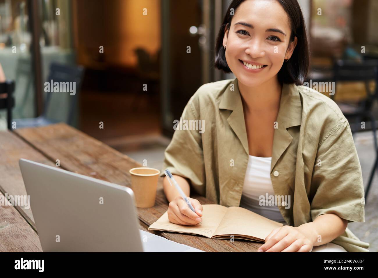 Portrait of young korean girl making notes, listening online meeting ...