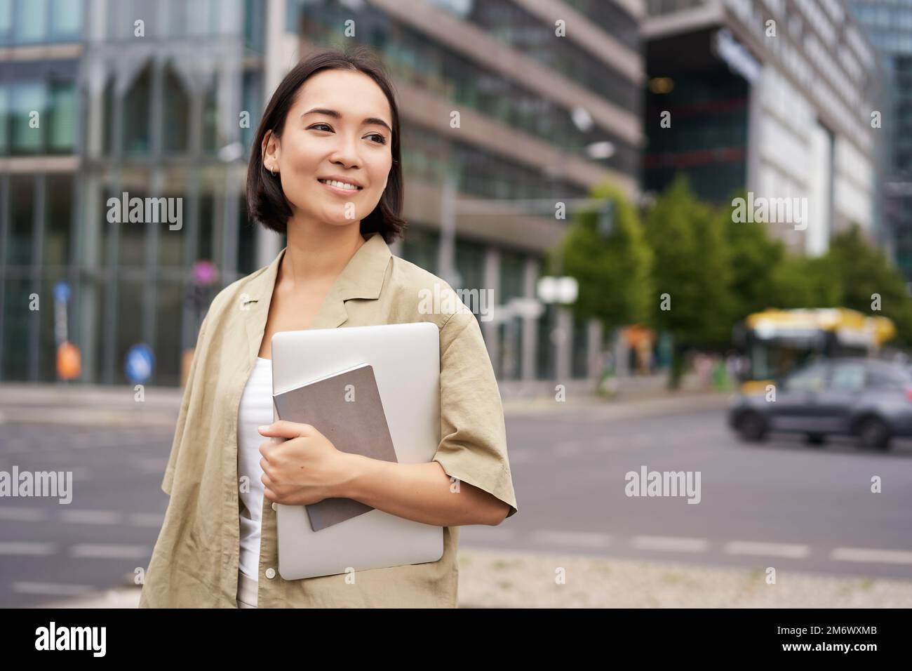 Portrait of beautiful asian woman standing on street with laptop and ...