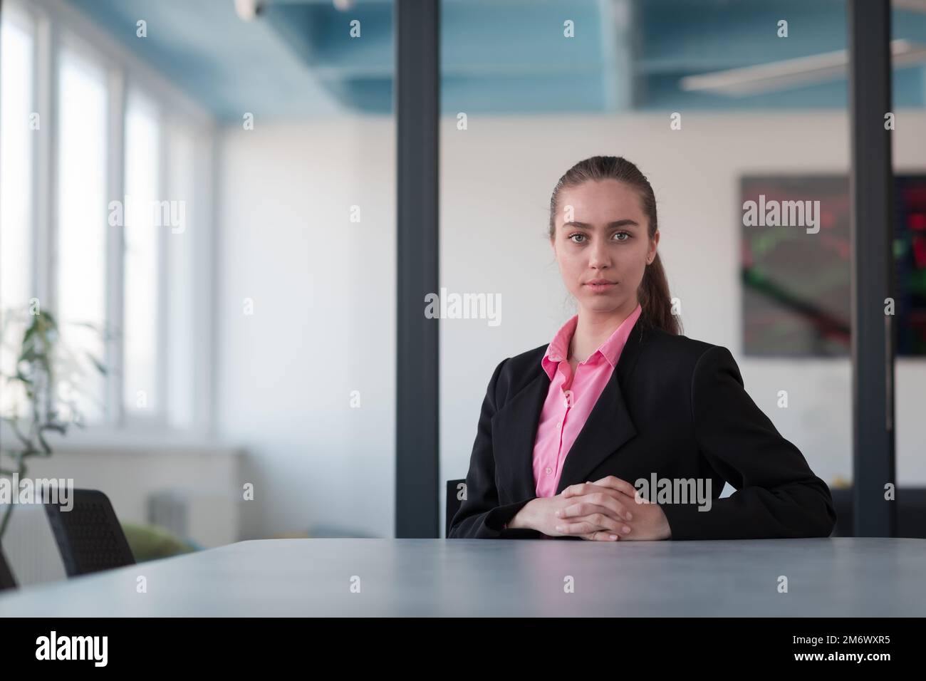 Successful young female leader in a suit with a pink shirt sitting in a ...