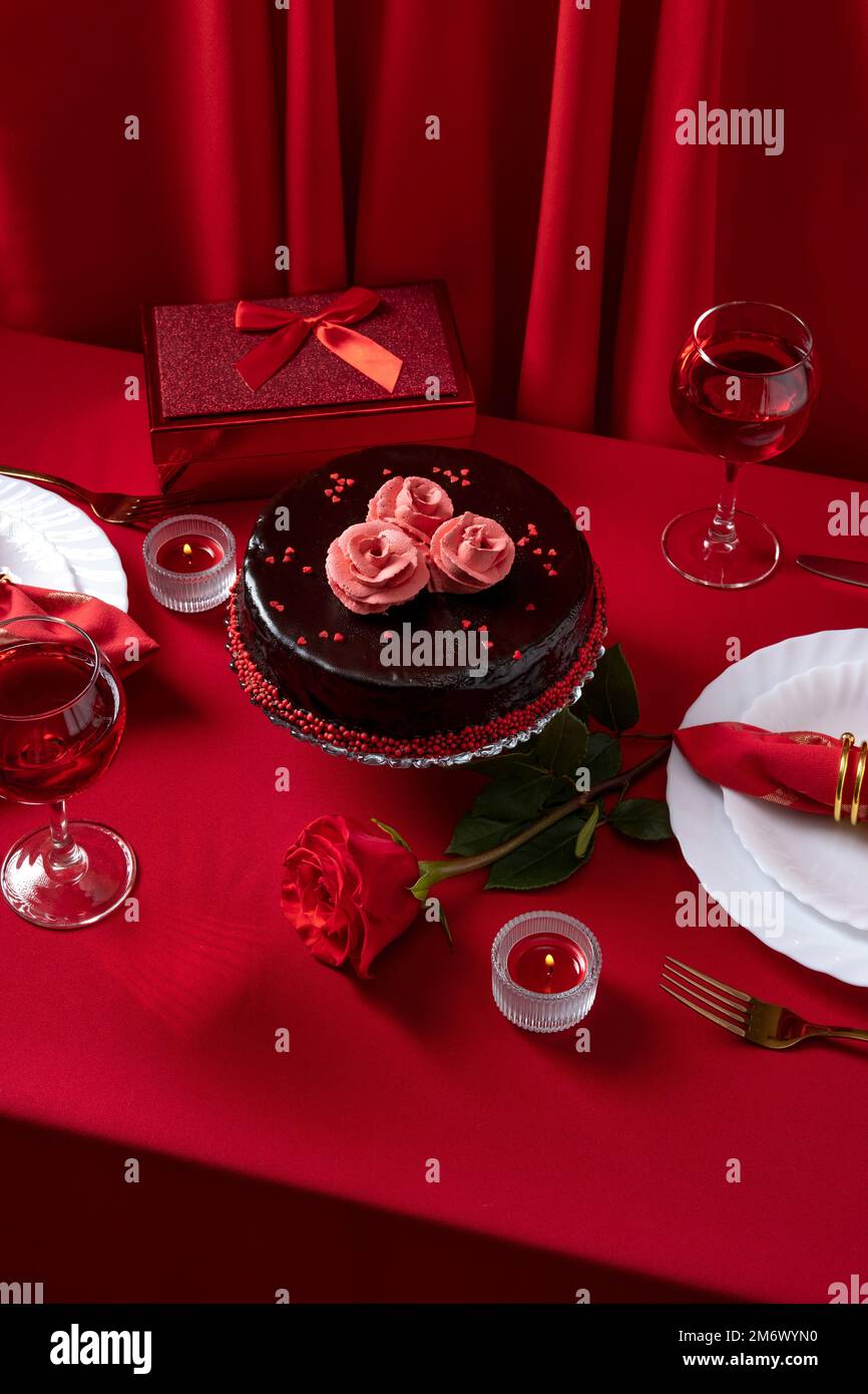 Romantic table setting with white dinnerware and red napkins, wine and candles. Valentines day ...