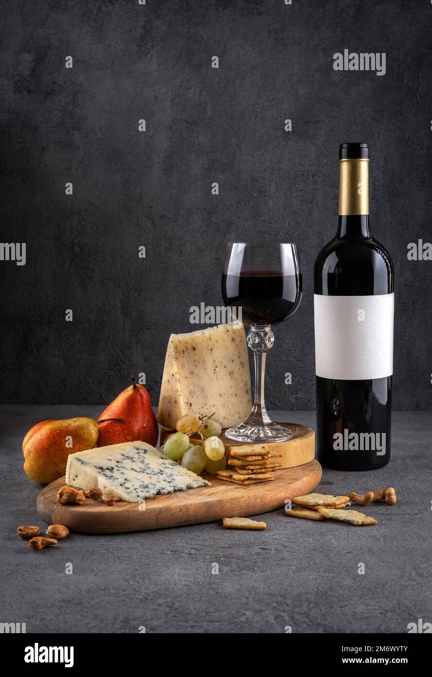 Glass and bottle of red wine with blue cheese and grapes on dark ...