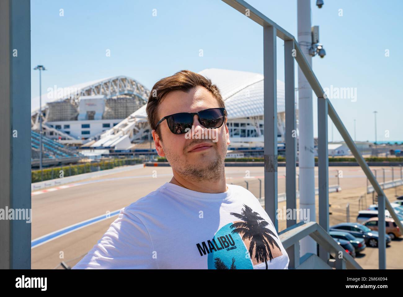 European caucasian white young male man in sunglasses on empty race car ...