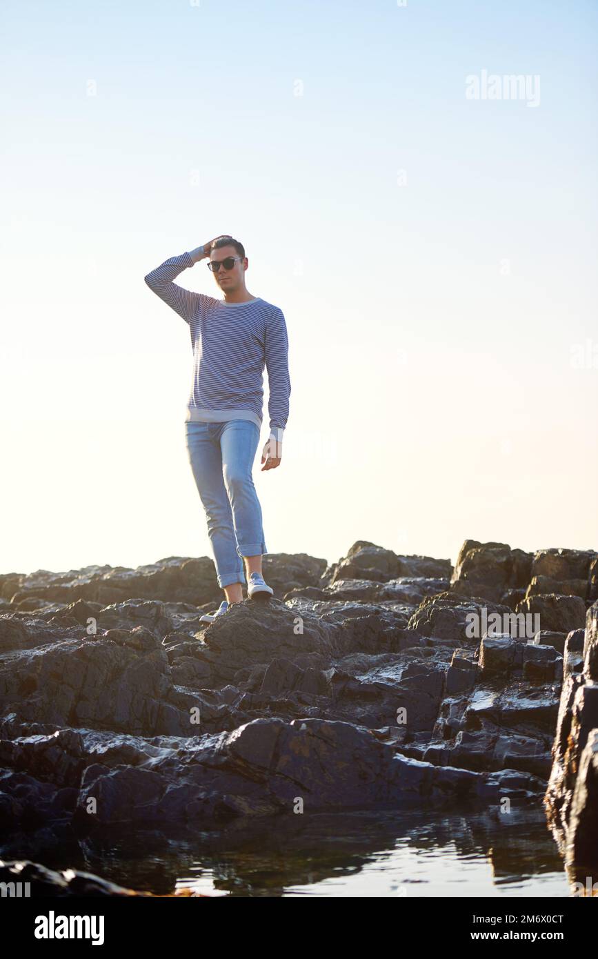Care to join me for a walk. a young man standing on the rocks by a ...