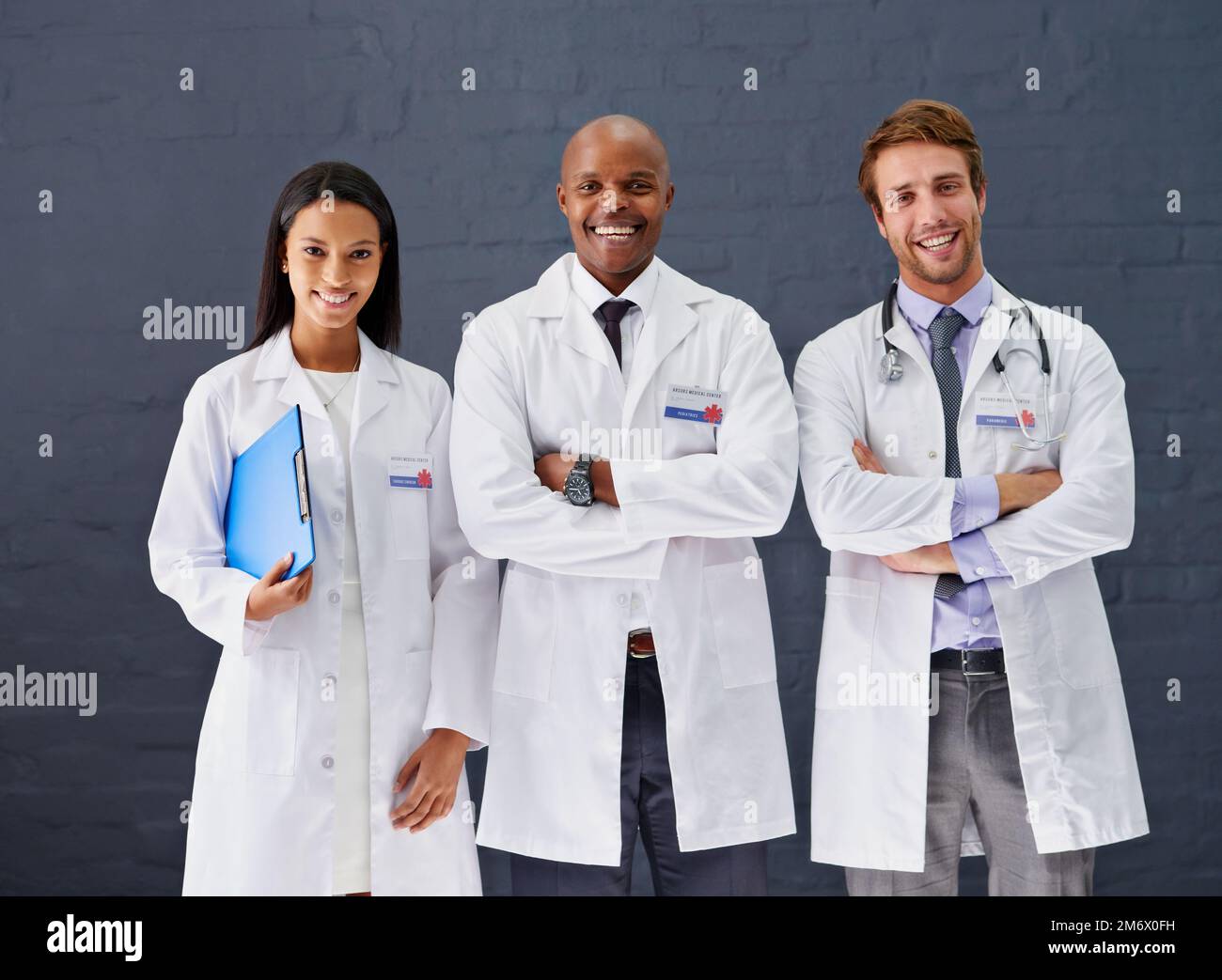 Medical confidence. Portrait of three doctors standing against a gray ...