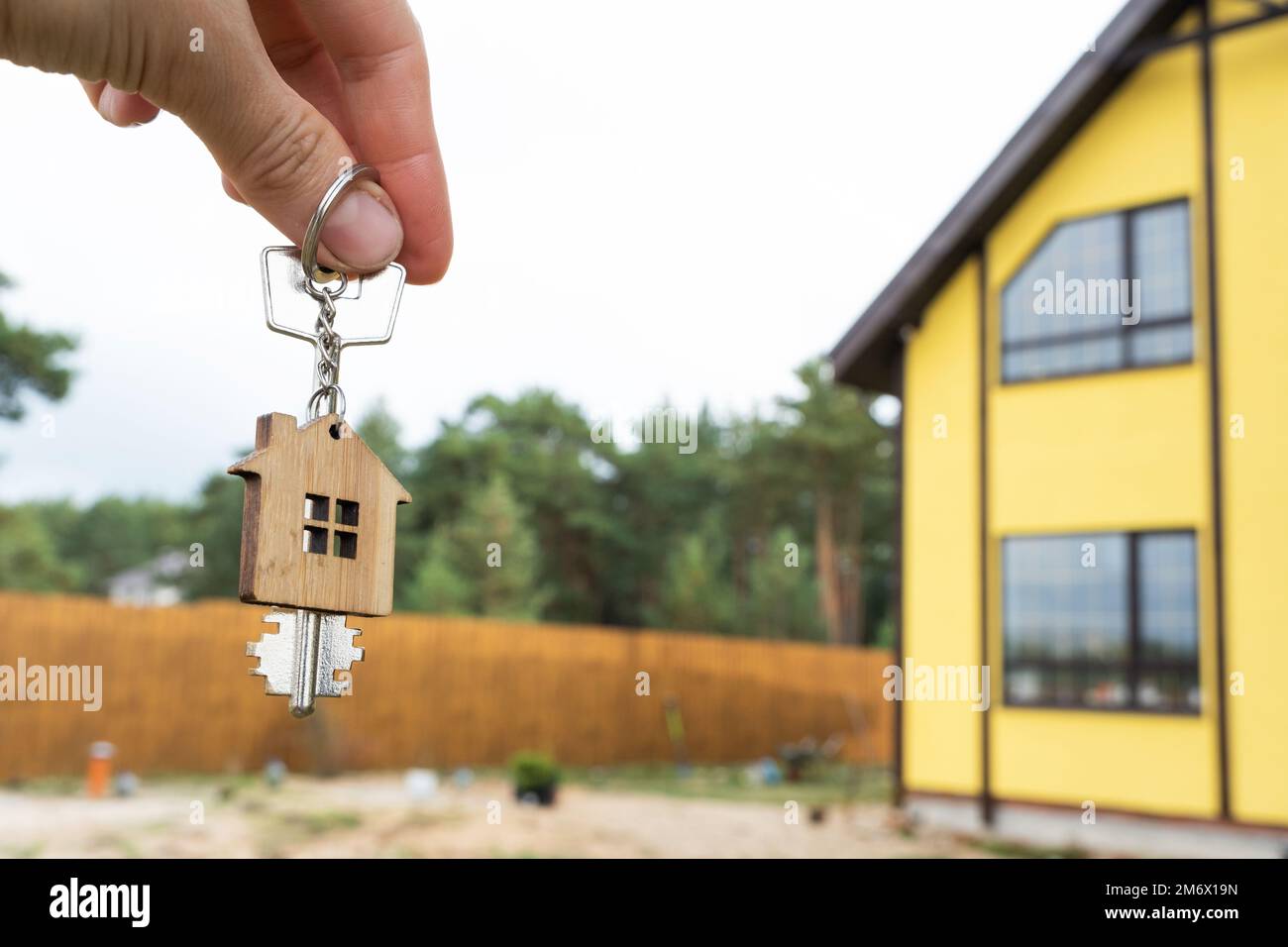 A hand with the keys to a new house on the background of an unfinished ...