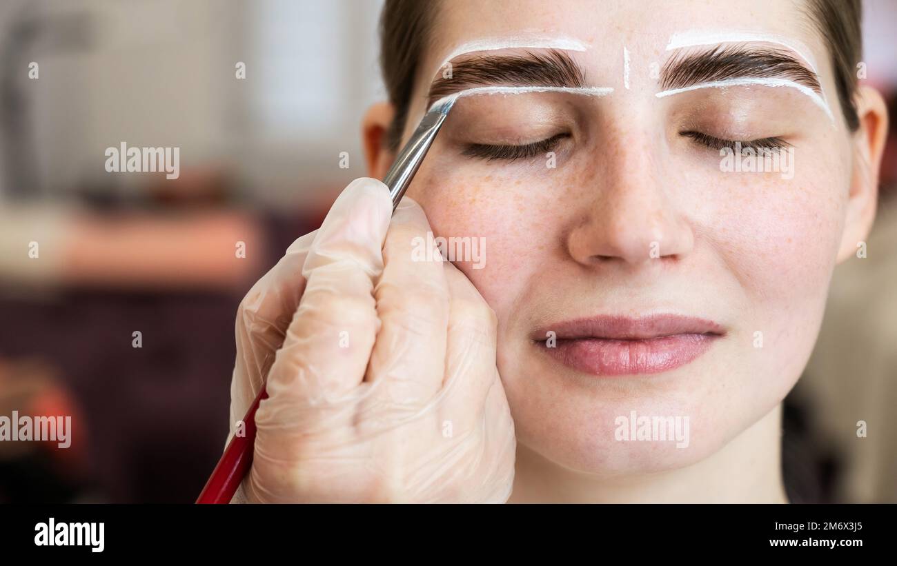 The master draws the shape of the eyebrows with white paint before ...