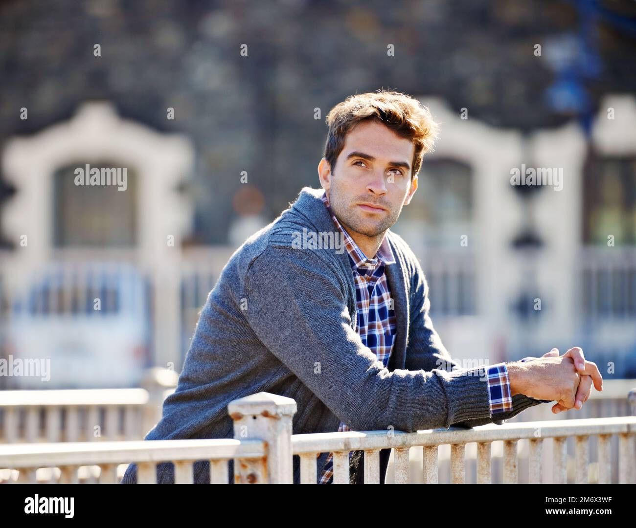 Thinking things over. a handsome young man leaning over a railing Stock ...