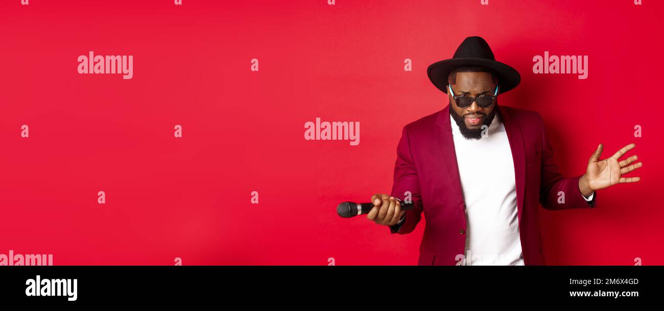 Passionate black male singer performing against red background, singing ...