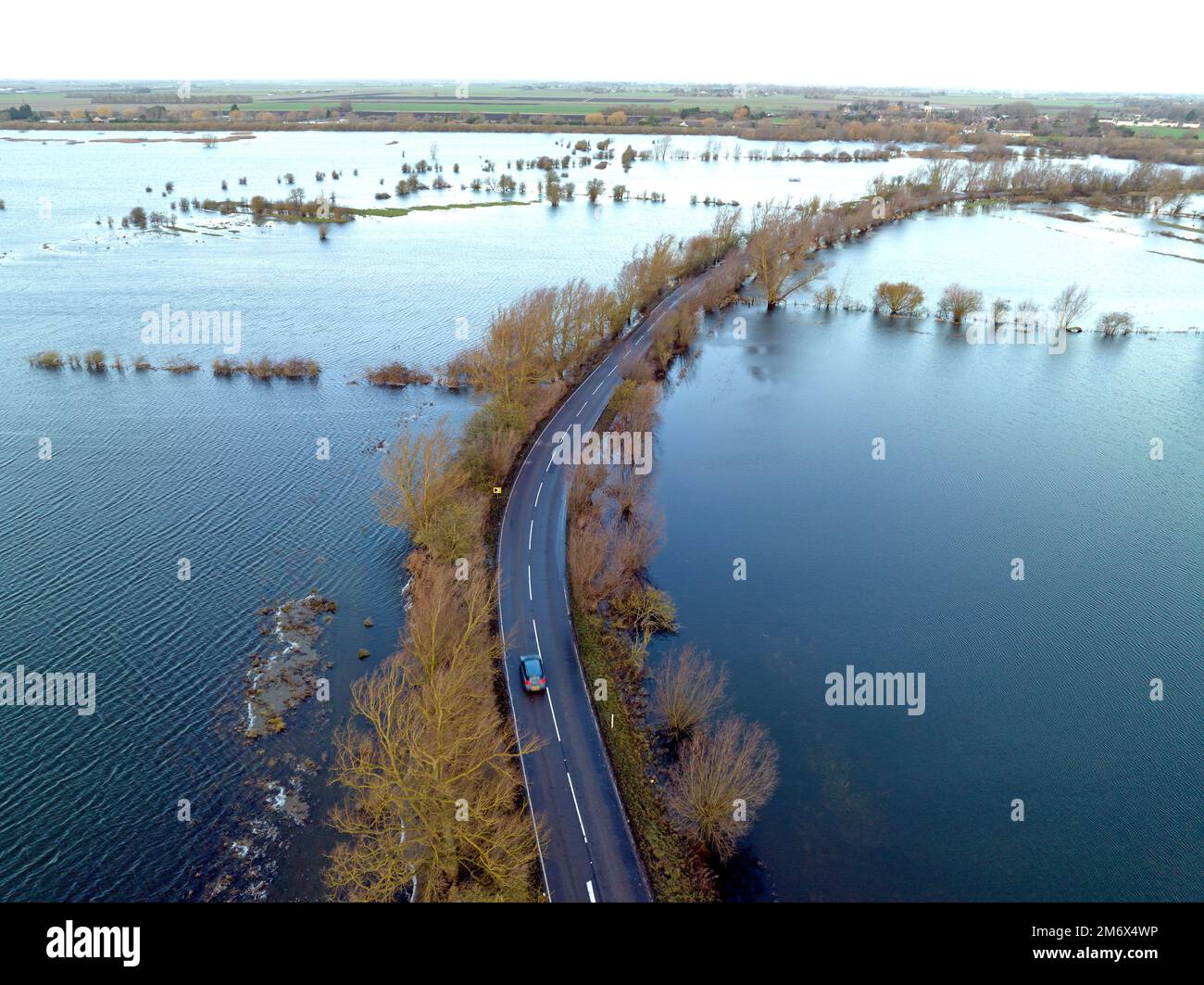 A car drives along the road as the Welney wash fills with floodwater as ...