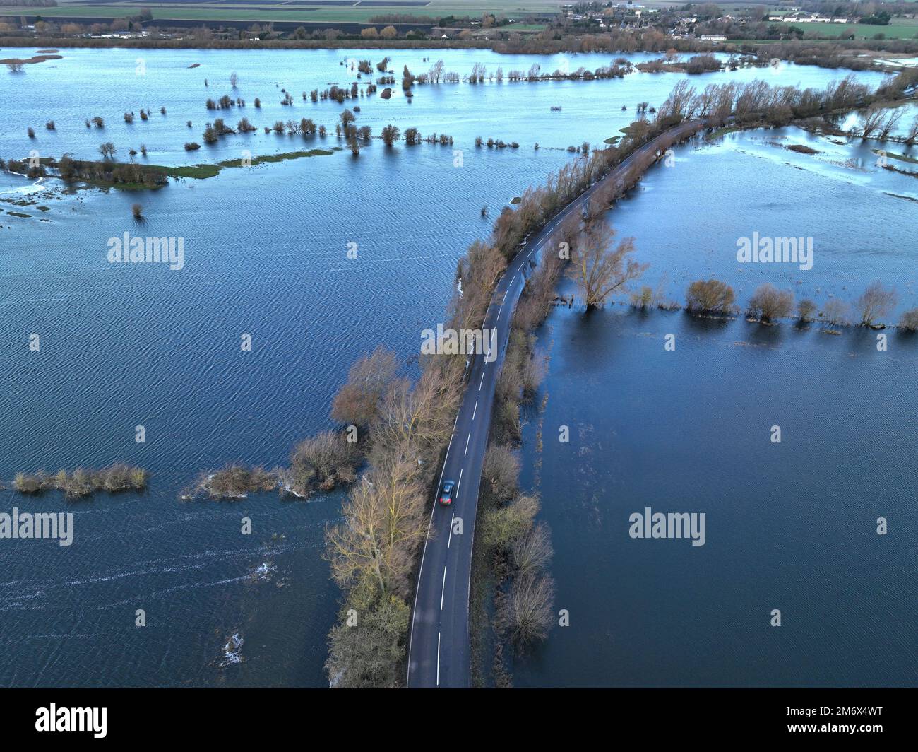 A car drives along the road as the Welney wash fills with floodwater as ...
