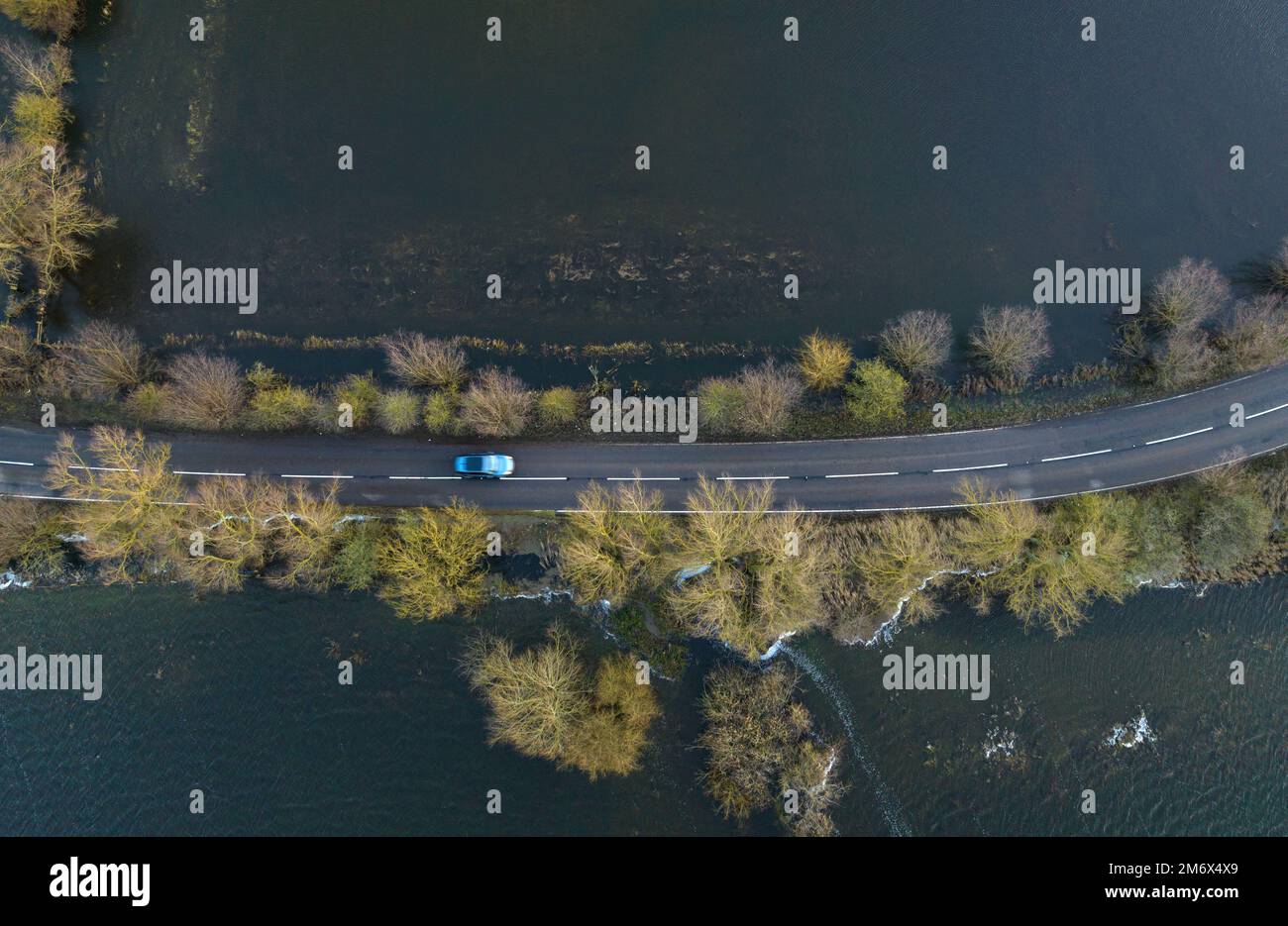 A car drives along the road as the Welney wash fills with floodwater as ...
