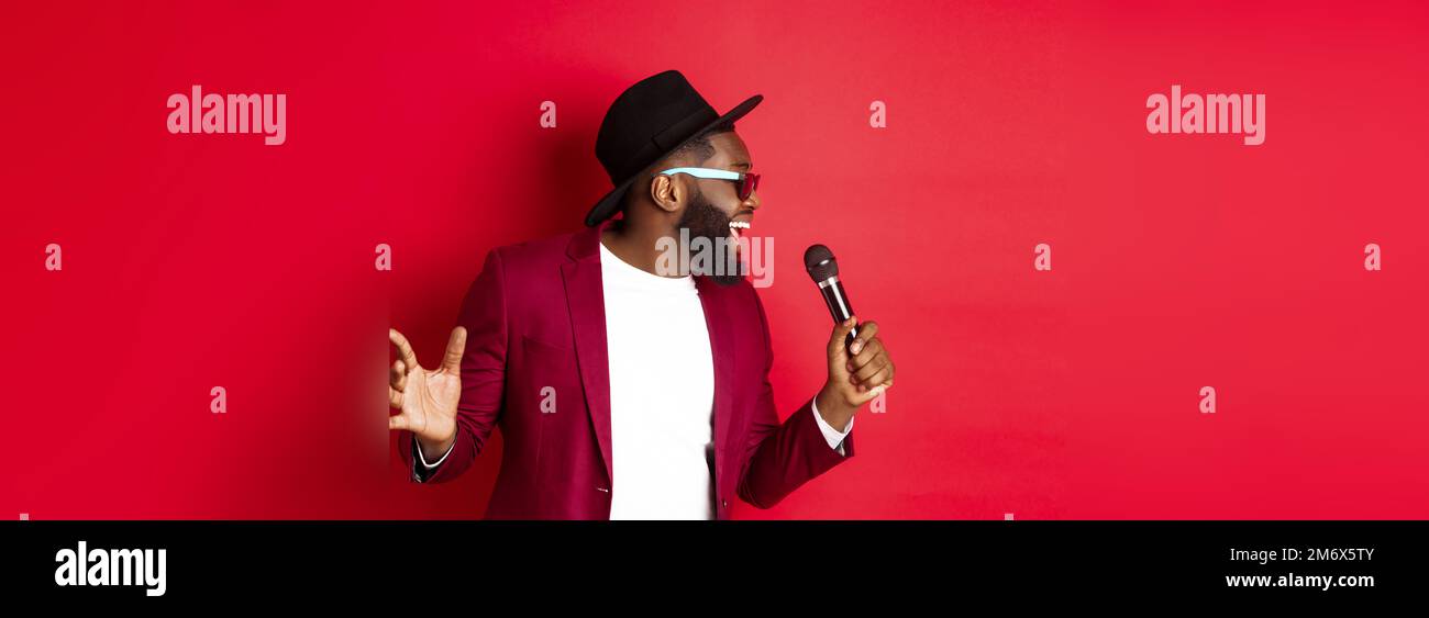 Passionate black male singer performing against red background, singing ...