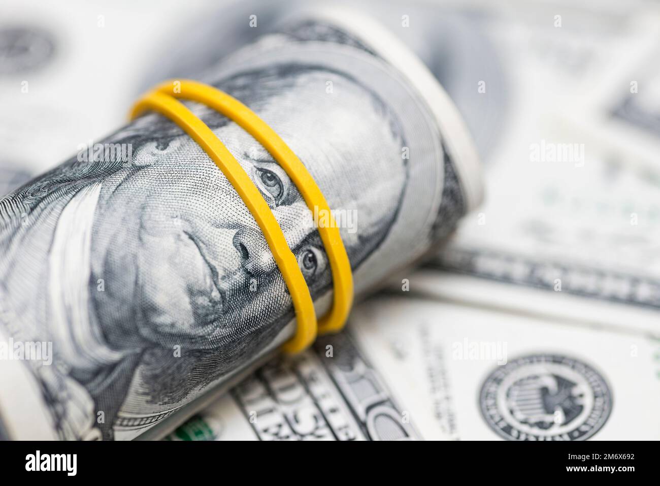 A roll of 100 dollar bills closeup on pile of American dollars ...