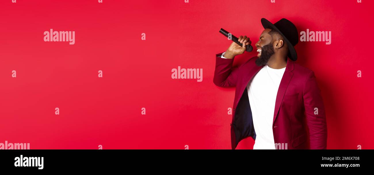 Passionate black male singer performing against red background, singing ...