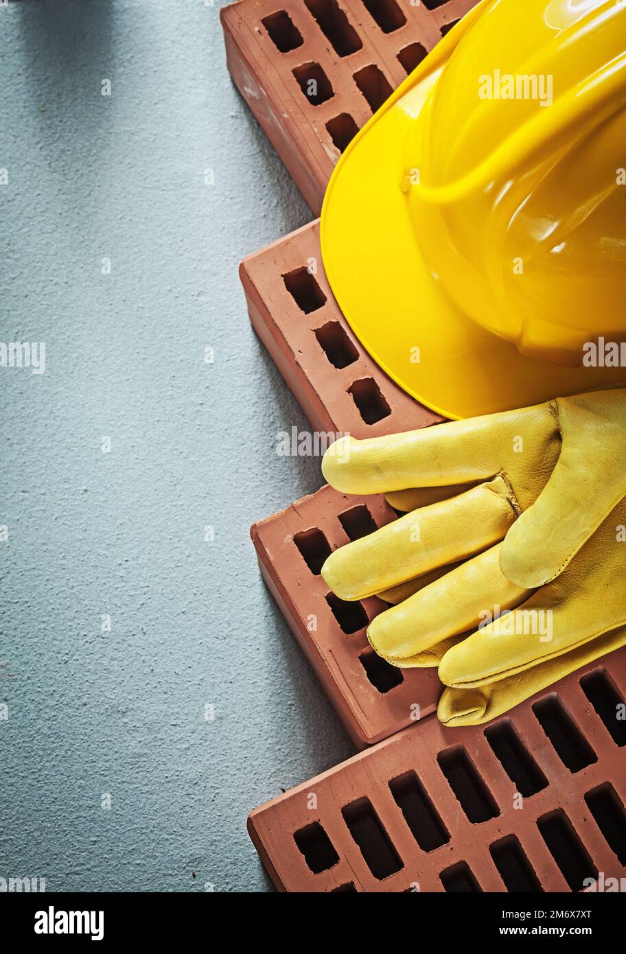 Assortment of building bricks protective cap safety gloves on concrete ...